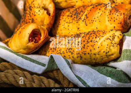 Sausages baked in dough sprinkled with salt and poppy seeds and bowl ...