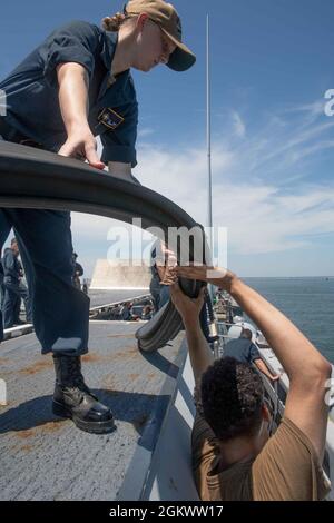 US Navy Three flight deck personnel hold the slack for a team ...