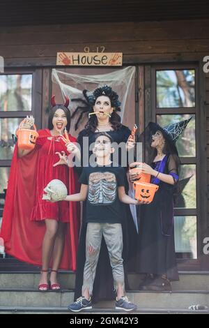 family in spooky costumes holding halloween attributes while growling ...
