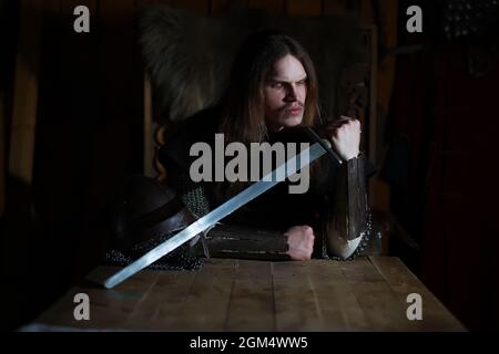 A mighty hero with long hair in chain mail armor in an ancient hall ...