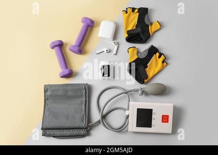 Pulse oximeter, dumbbells and bicycle gloves on color background Stock Photo - Alamy
