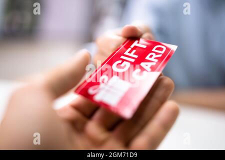 Hand Giving Gift Voucher Card. Holding Prepaid Coupon Stock Photo - Alamy