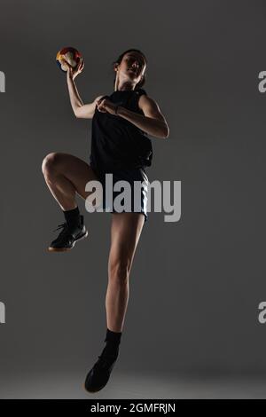 Handball player posing on gray background. Girl jumping with ball Stock ...