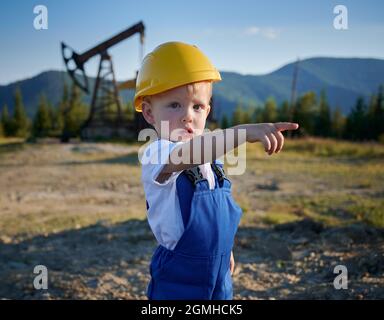 Cute boy construction worker in a yellow hard hat stands in an indoor ...