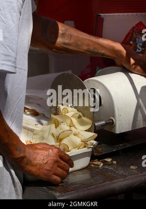 A food booth workers prepares potatoes before cooking them in oil as ...