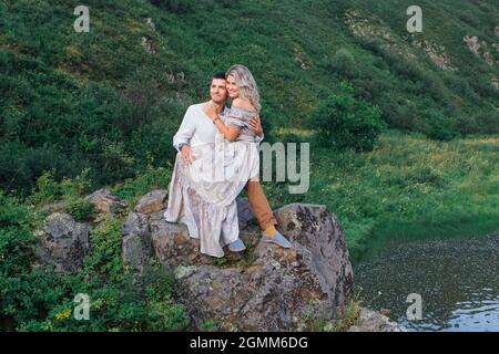 Beautiful romantic inloved couple sitting on rocks by the river. Copy ...
