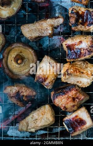 Top view of barbequed vegetables and meat on a white plate with cutlery ...