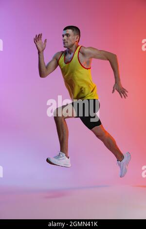 Developing endurance. Male athlete in motion isolated over gray studio ...