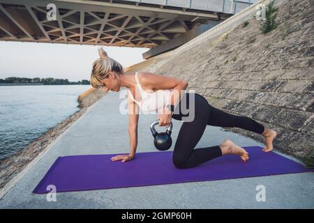 Woman exercising kettlebell pilates outdoor Stock Photo - Alamy