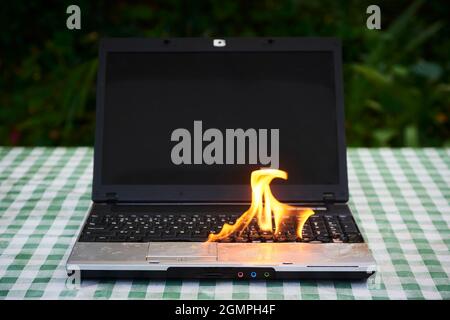 Laptop burning in flames on a desk, fire hazard. losing valuable data ...