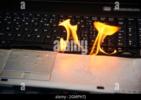 Laptop burning in flames on a desk, fire hazard. losing valuable data ...