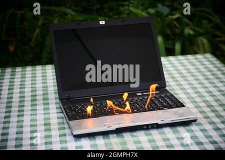 Laptop burning in flames on a desk, fire hazard. losing valuable data ...