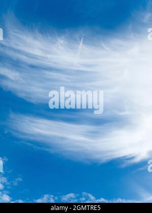 Airplane with condensation trails and feather clouds (Cirrus) in front ...