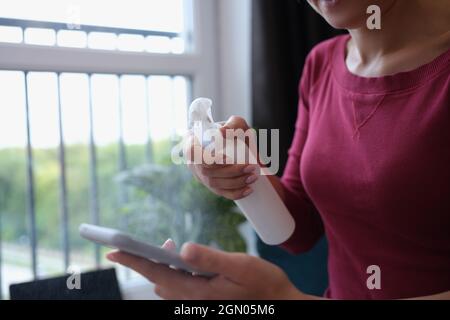 Woman with smartphone and antiseptic spray on pink background, top view ...
