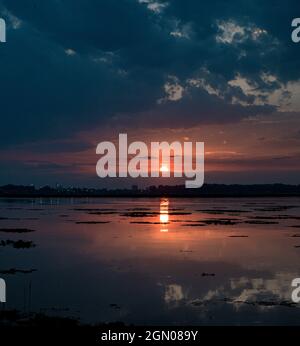 Sunset on the lake. Beautiful sunset behind the storm clouds before a ...