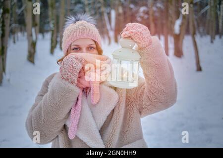 A happy woman stands with a lantern in her hands, a winter park with ...