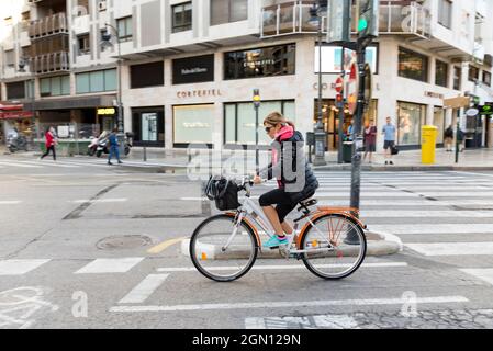 Valencia, Spain. 21st Sep, 2021. A woman wearing a mask rides a bicycle past the Mercado de ...