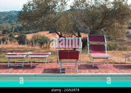 Red sunbeds by the pool in the Italian countryside (Tuscany, Italy ...