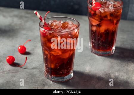 Cold refreshing cherry cola in a glass with ice on a stone background ...