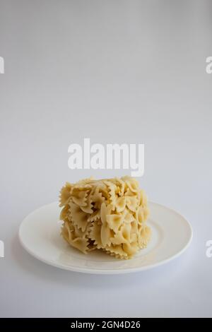 Cooked farfallini pasta in a shape of cube on a white plate. Copy space ...