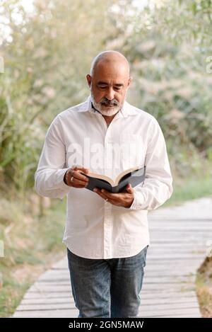Man reading a book while standing outside next to a bicycle ca. 1962 ...