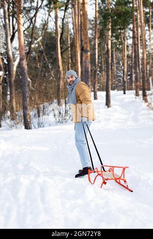 Young man pulling knit hat on cheerful girlfriend with eyes closed ...