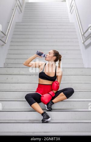 Boxing athlete with water bottle, tired after workout, training or ...