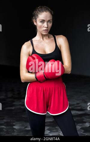 Female boxer portrait with crossed arms in a boxing ring. Fighting ...