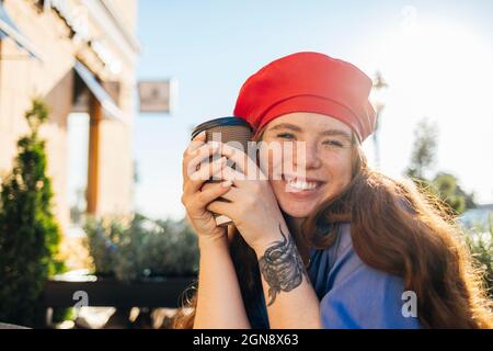 Young woman in cap with disposable electronic cigarette on pink ...