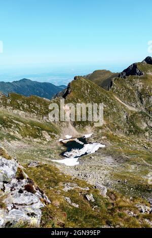 Rocky mountainside covered with grass and melting snow Stock Photo - Alamy