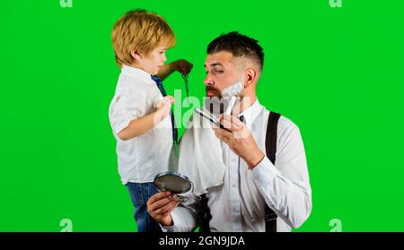 Son and father in barber shop. Shaving in barbershop. Assistant for dad ...
