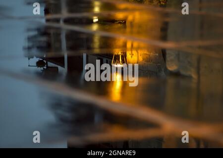 Closeup shot of a puddle reflecting nighttime lighting in the city ...