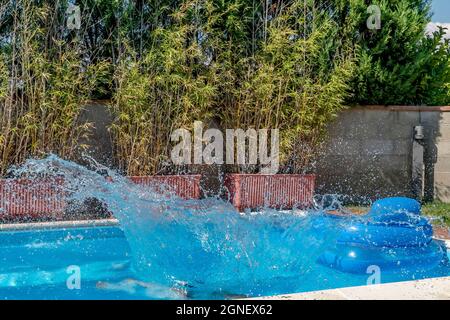 A huge splash of water is created by a cannonball dive into a swimming ...
