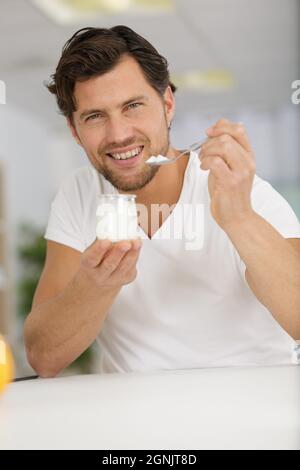 Handsome man eating delicious yogurt on light grey background Stock ...