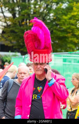 older man wearing pink suit and feather boa makes phone call at ...