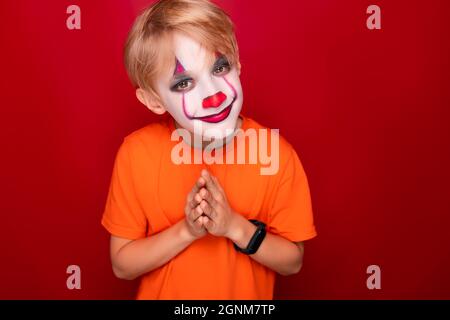 sly boy with halloween makeup put his palms together in front of him ...