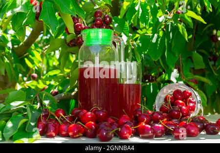 Harvested ripe sweet cherries and decanter of juice in garden Stock ...