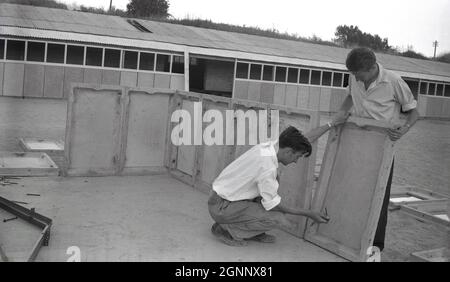 1960s, historical, constructing a prefab garage on an industrial ...