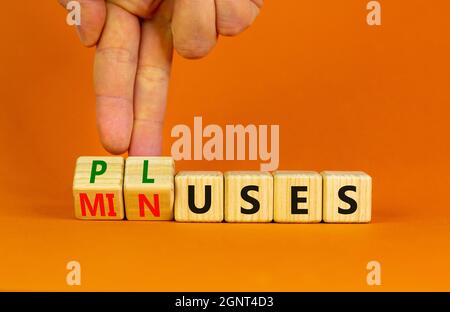 Pluses and minuses symbol. Businessman turns wooden cubes and changes ...