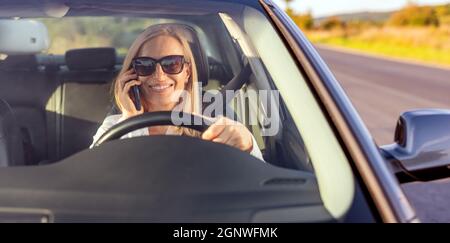 Woman talking on smartphone while driving modern car, view from outside ...