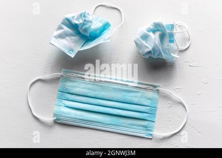new and used medical masks and antiseptic gel on white background ...