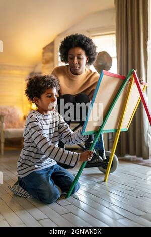 African American woman math teacher writing on black board with marker ...