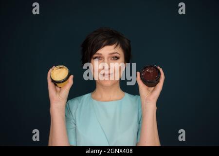 woman beautician holding jars of creams and face masks in her hands ...