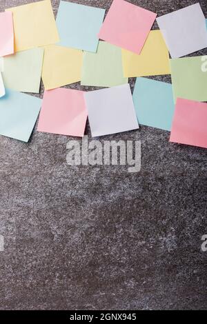 Many blank multicolored paper stick note list on concrete wall ...