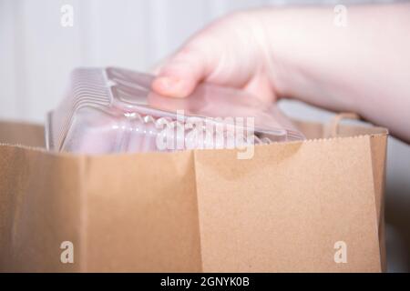 Woman pulling a fresh pastry box out of a grocery bag Stock Photo - Alamy