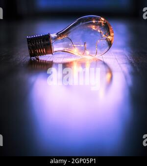 LED light bulb is lying in the bed, hands touching. Symbol for ideas ...