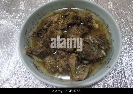 Top view of siri paaye or paya dish garnished with diced ginger, long ...