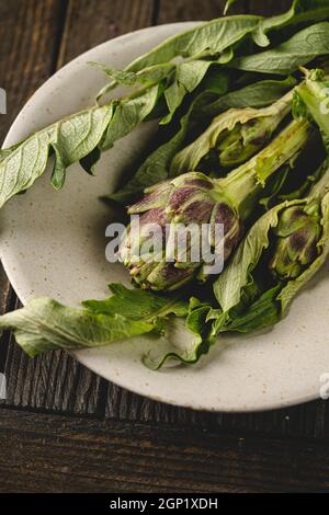 fresh baby artichoke with leaves on rustic textile background Stock ...