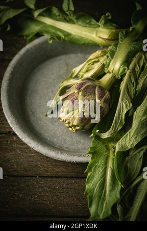 fresh baby artichoke with leaves on rustic wooden background Stock ...