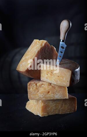 Chunks of hard, perennial cheese on a black background. The cheese is ...
